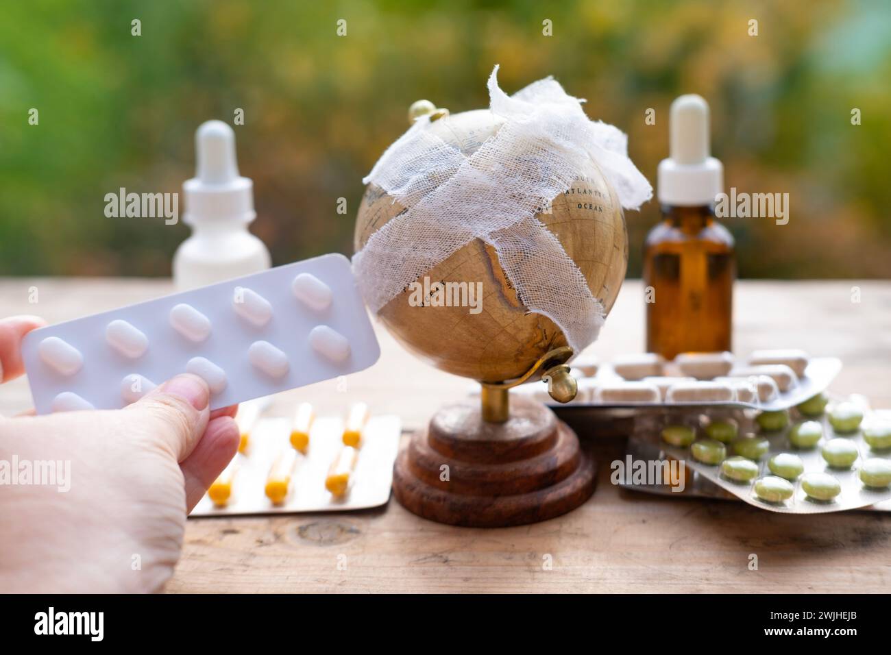 doctor's hand holding out blister pills, bandaged globe, planet sick ...