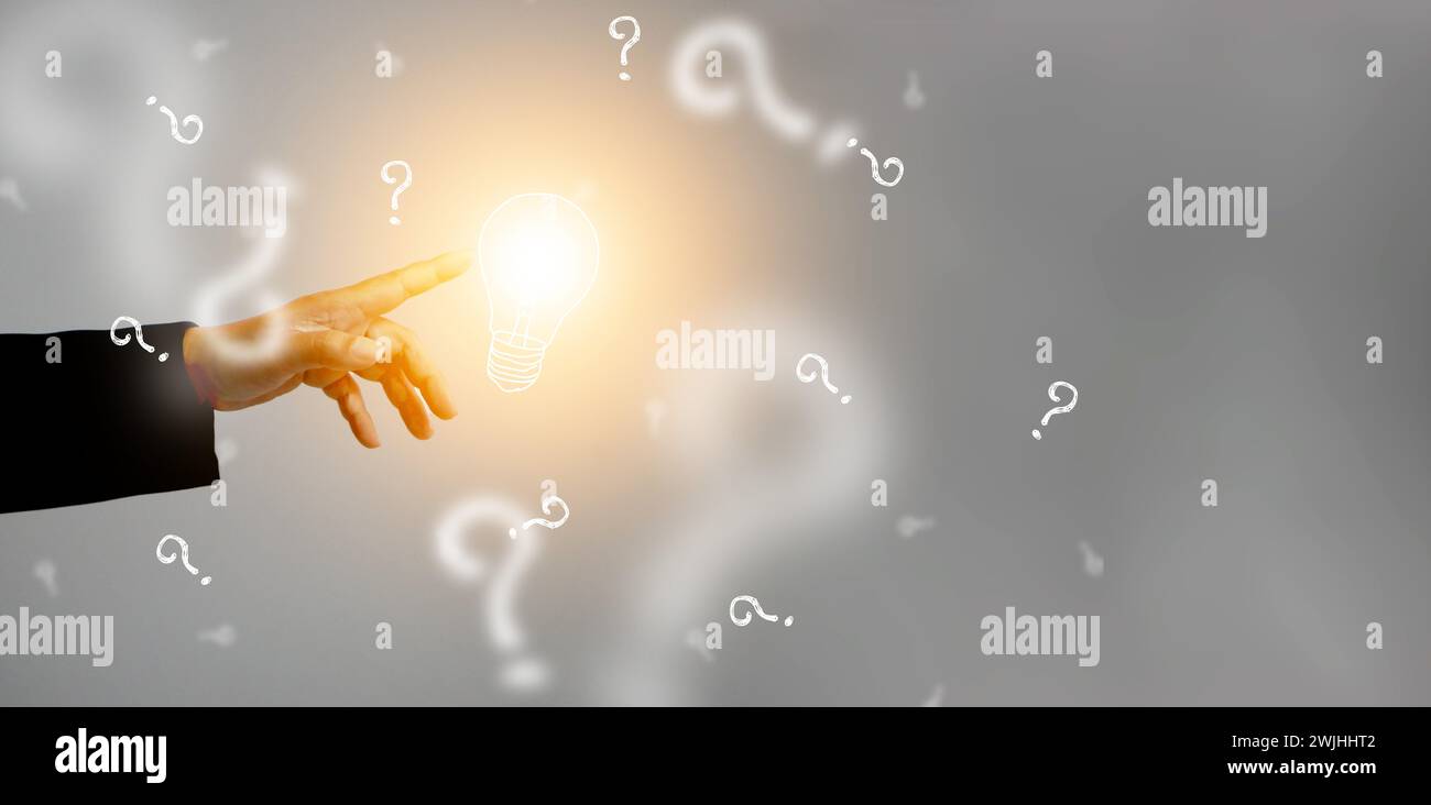 Idea concept. Hand touches an illuminated light bulb surrounded by ...