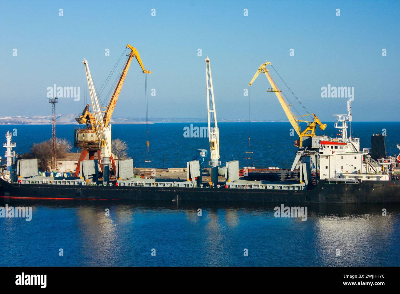 Cargo ship loading containers at bustling seaport. Industrial cranes ...