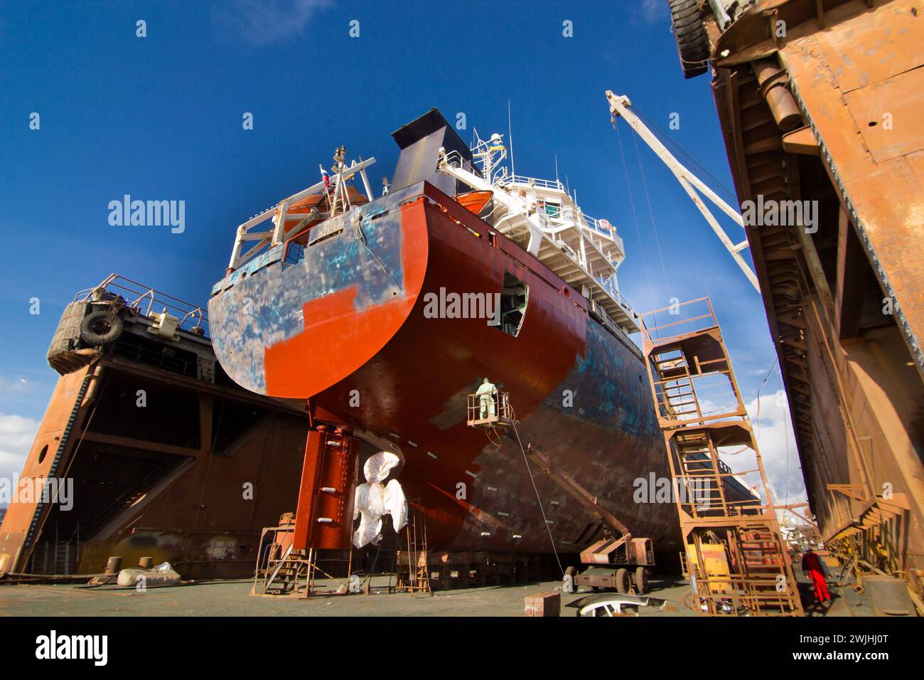 Commercial vessel undergoes maintenance in floating dock. Workers paint ...
