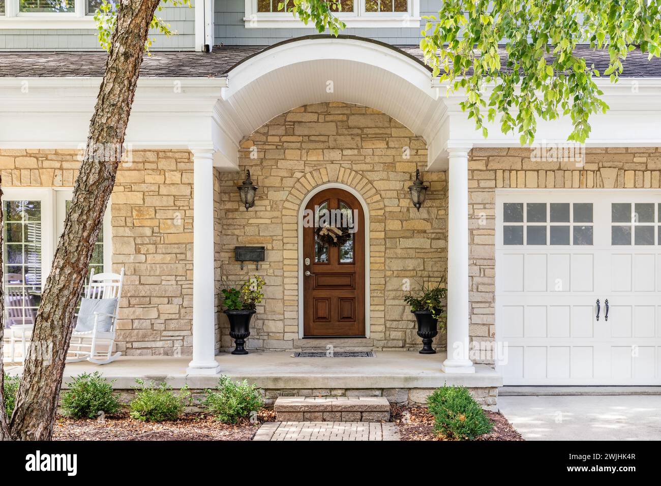 A front door detail with a rounded facade and front porch, a stone and ...