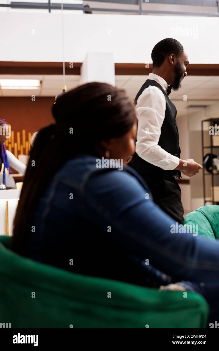 African American hotel staff and guest in lobby. Woman traveler waiting ...