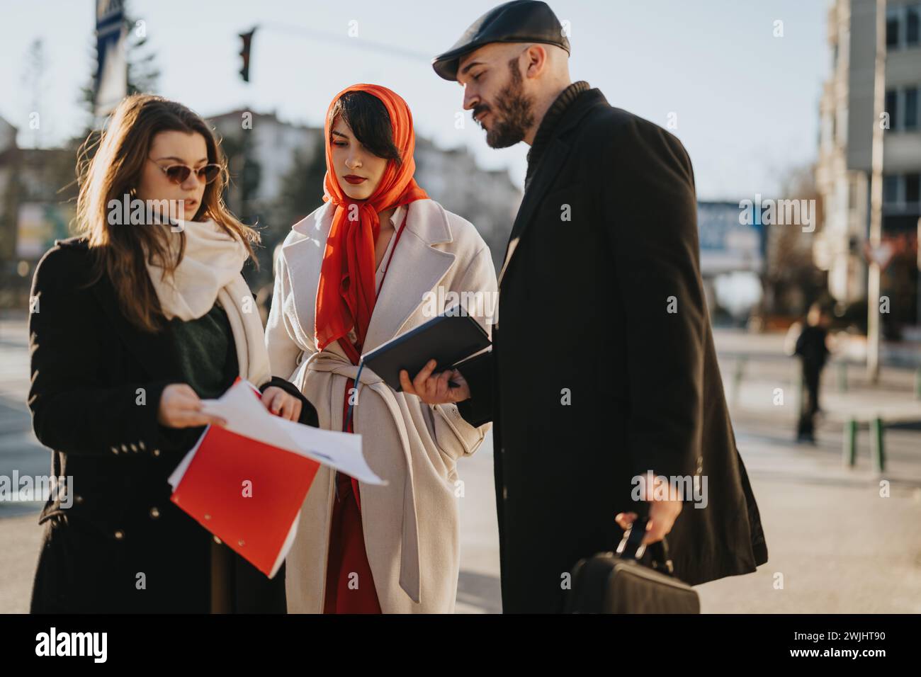 A group of young entrepreneurs engaged in a strategy discussion outside ...