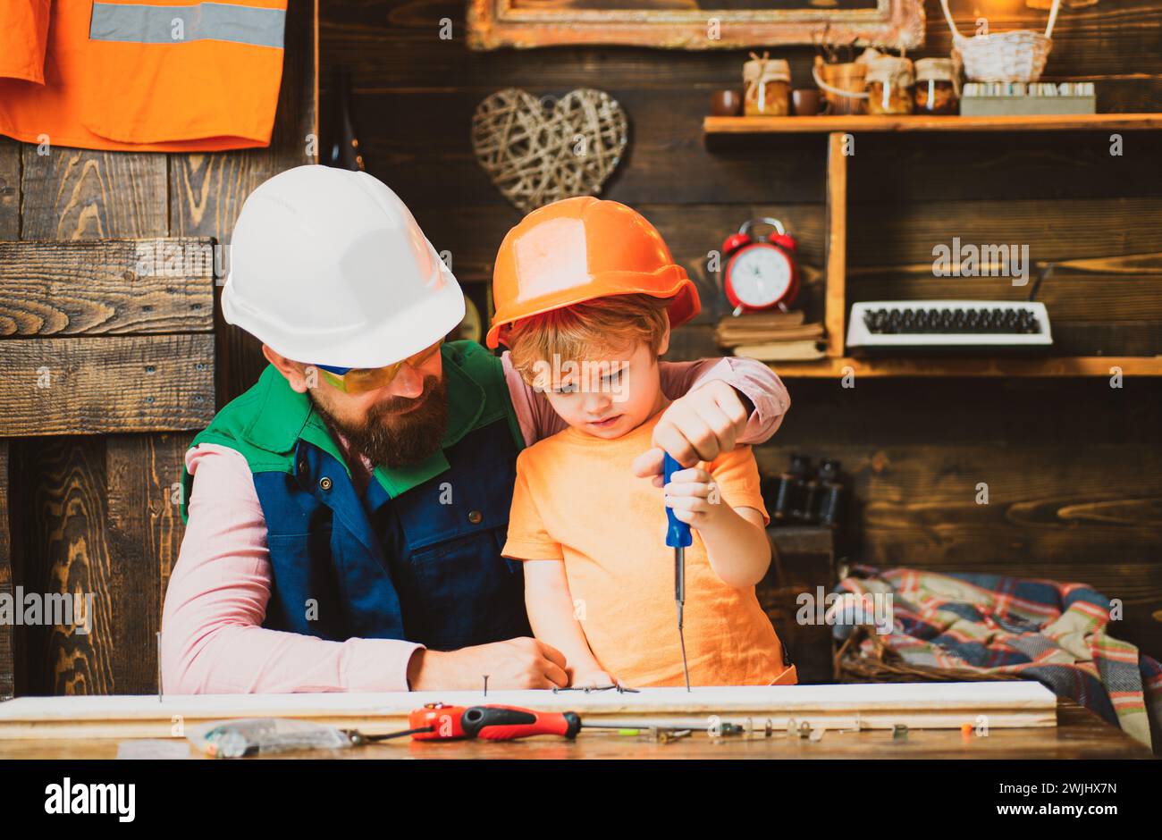 Father is teaching his son to use the screwdriver and hammer. Work with ...