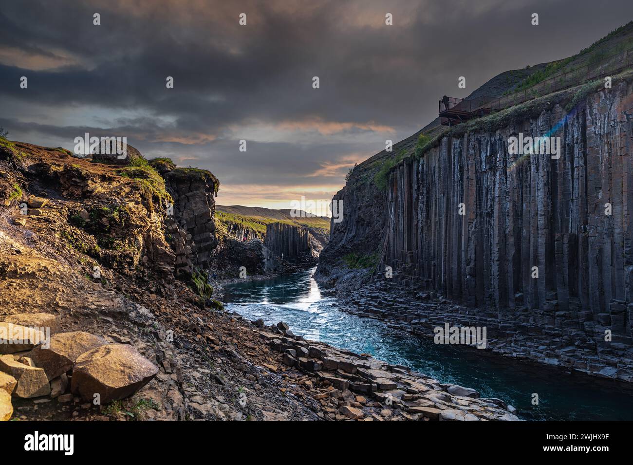 Sunset illuminates the towering basalt columns of Studlagil Canyon, a ...