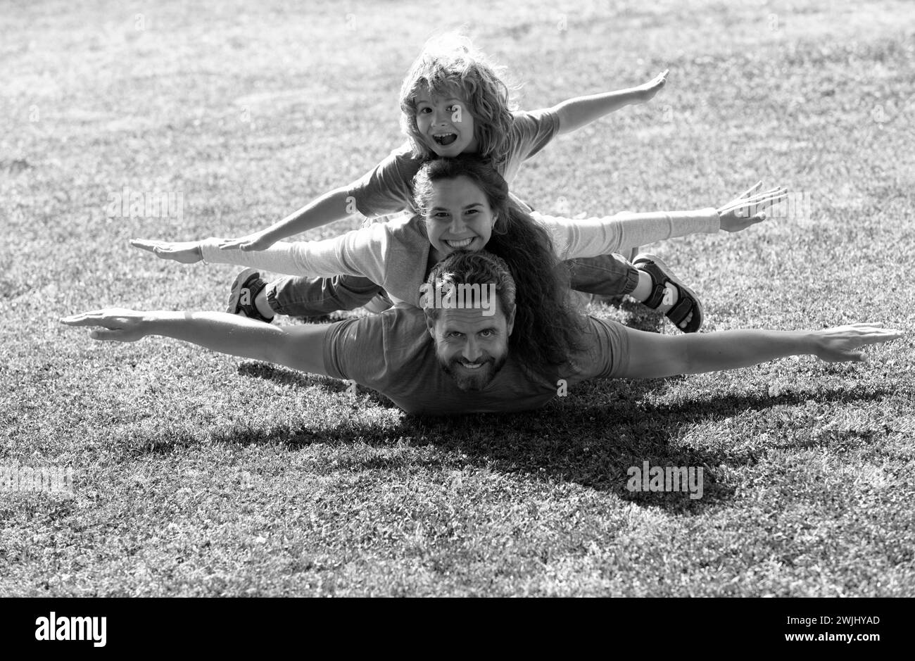 Family lying on grass in park. Fly concept, little boy is sitting ...