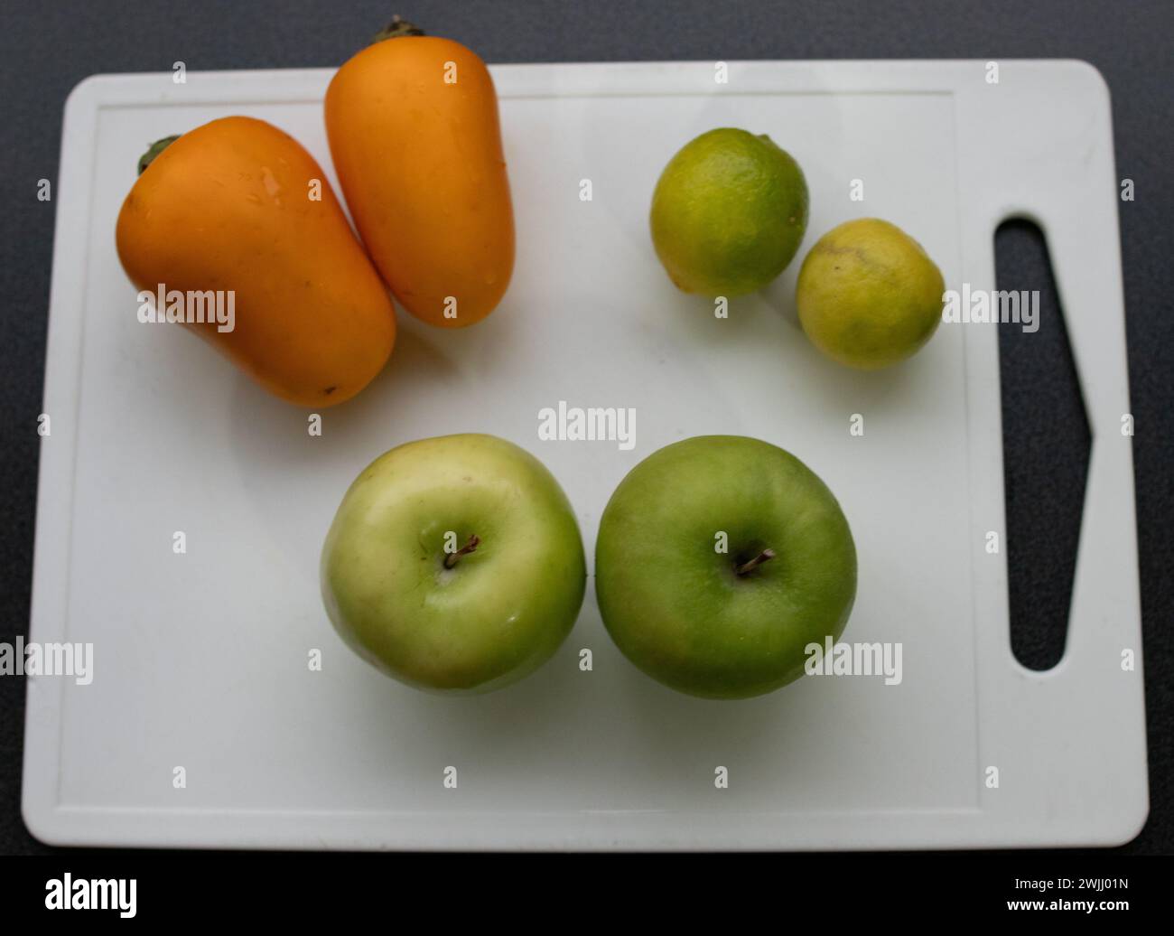 Closeup of two coconas, two limes and two green apples on a white ...