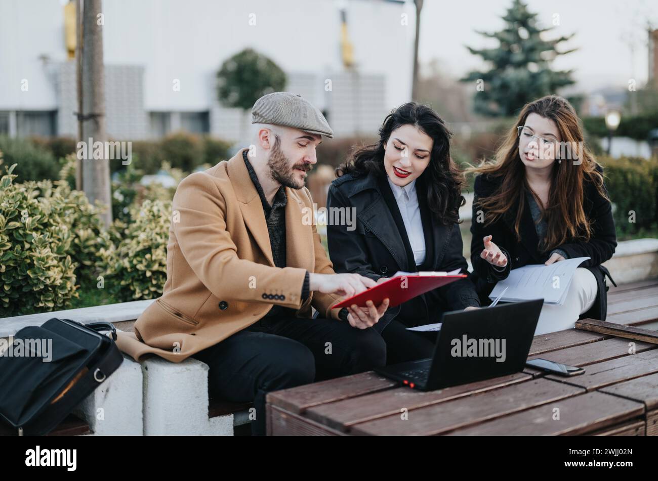 Three business professionals reviewing documents during outdoor ...