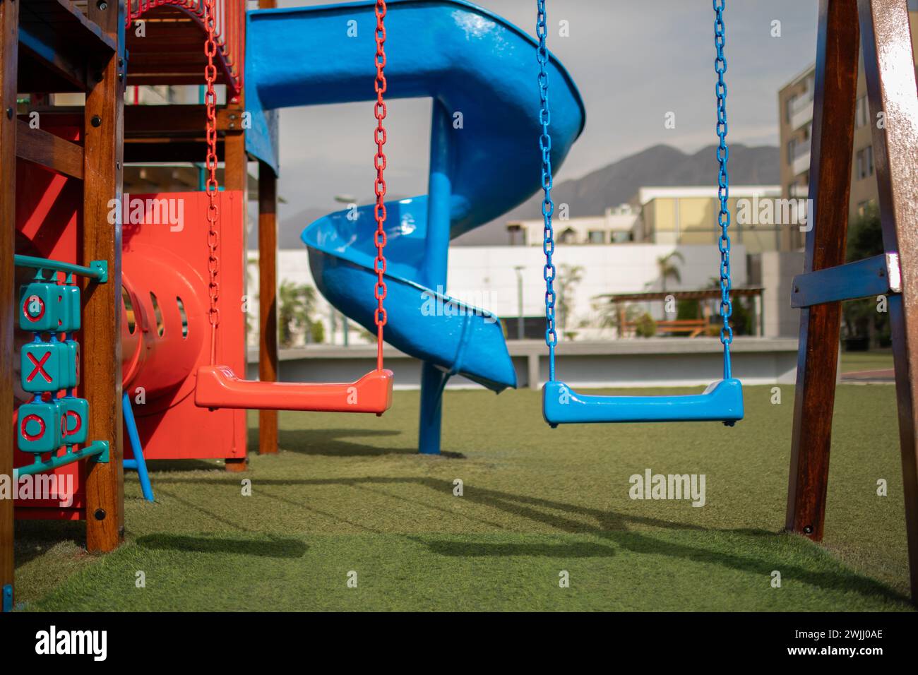 Closeup image of a red and a blue swing in a colorful playground Stock ...