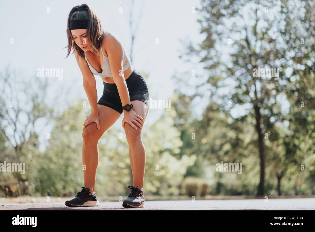 Girl resting after sprinting on race track in the park. Exhausted female runner concept Stock ...
