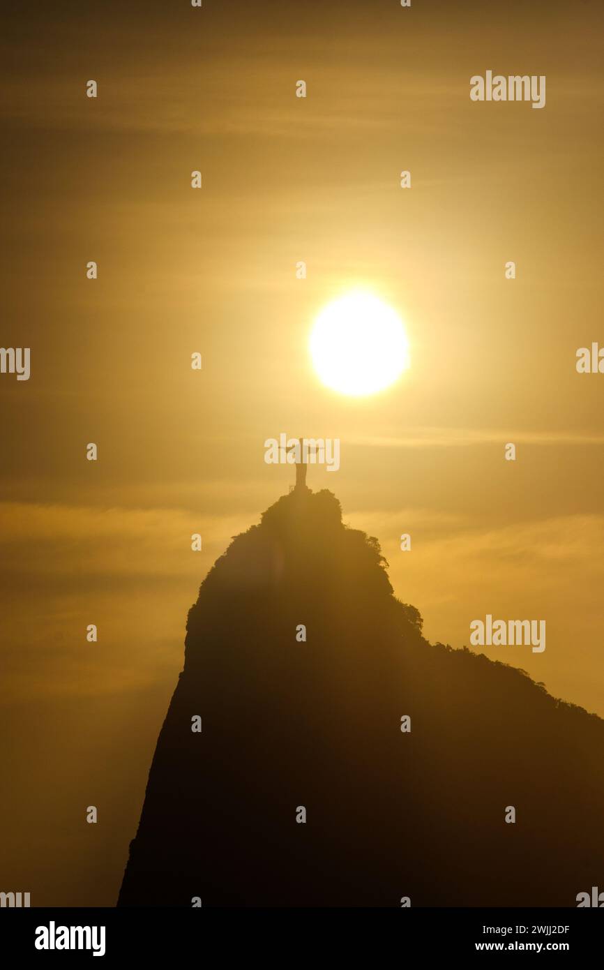 sun setting behind the statue of Christ the Redeemer in Rio de Janeiro ...