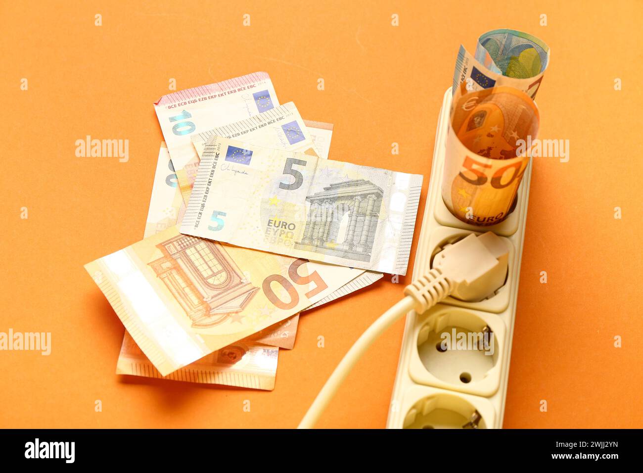 Power socket with euro banknotes and plug on orange background ...