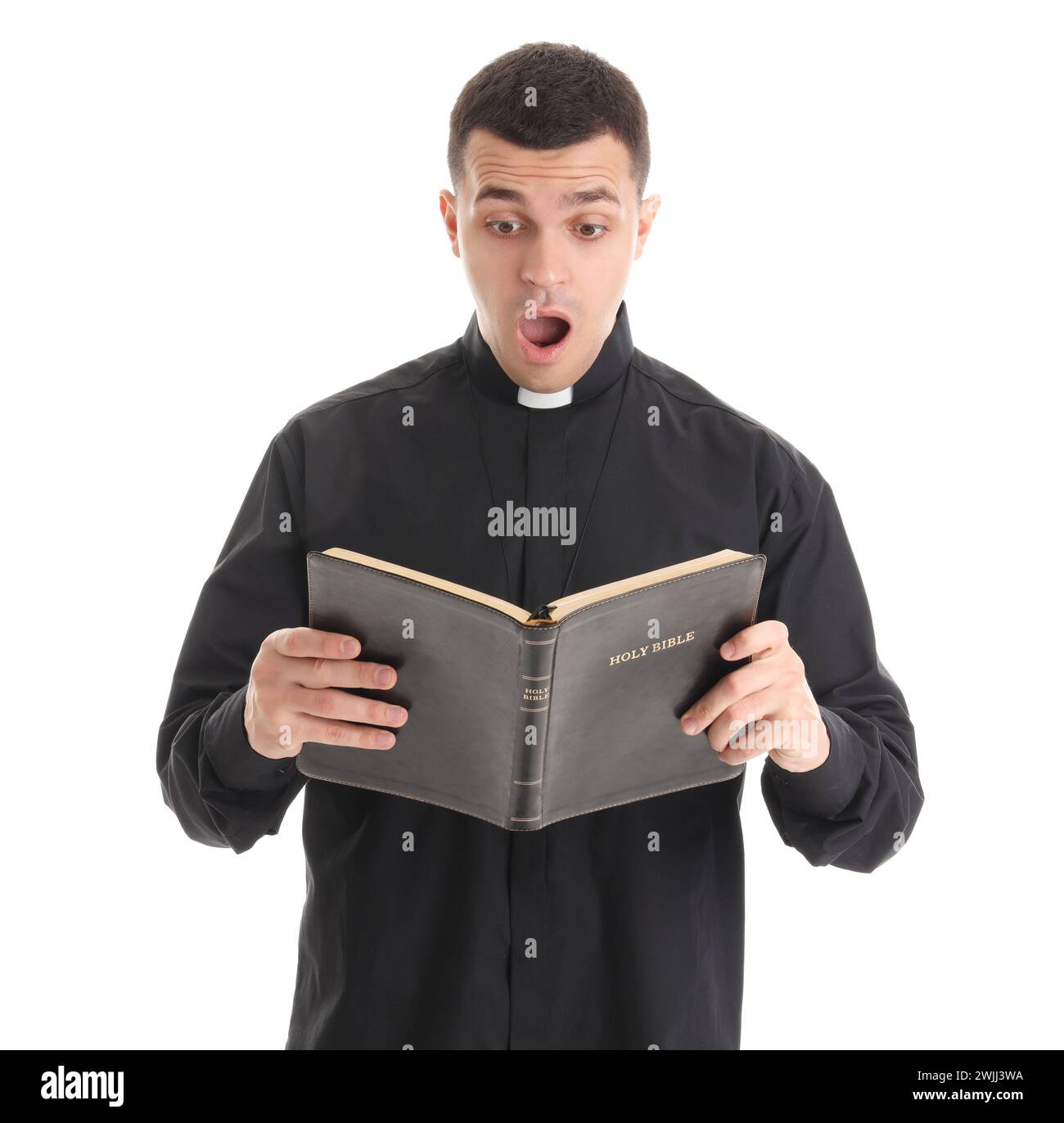 Shocked young priest reading Holy Bible on white background Stock Photo ...