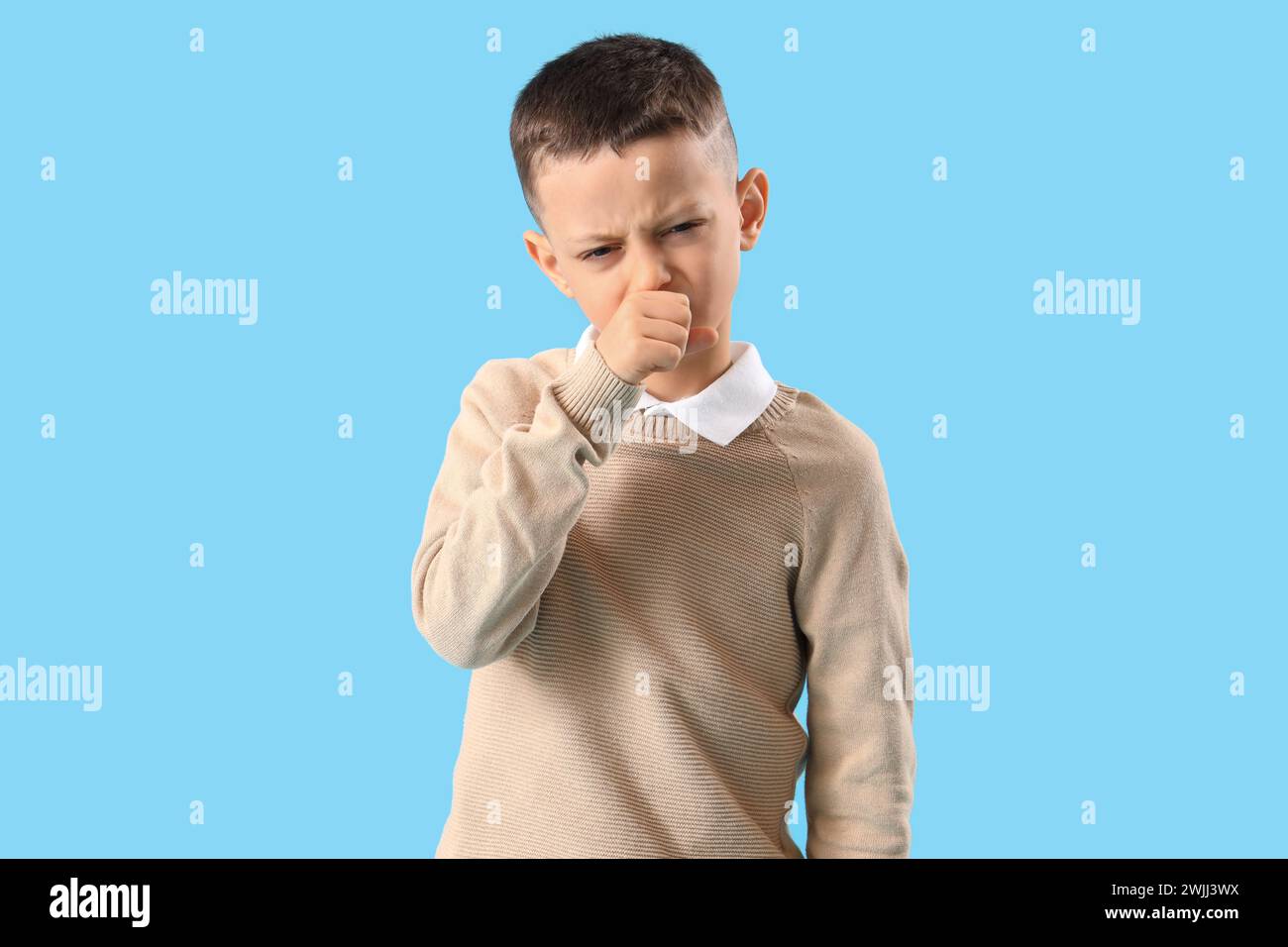 Ill little boy coughing on blue background Stock Photo - Alamy