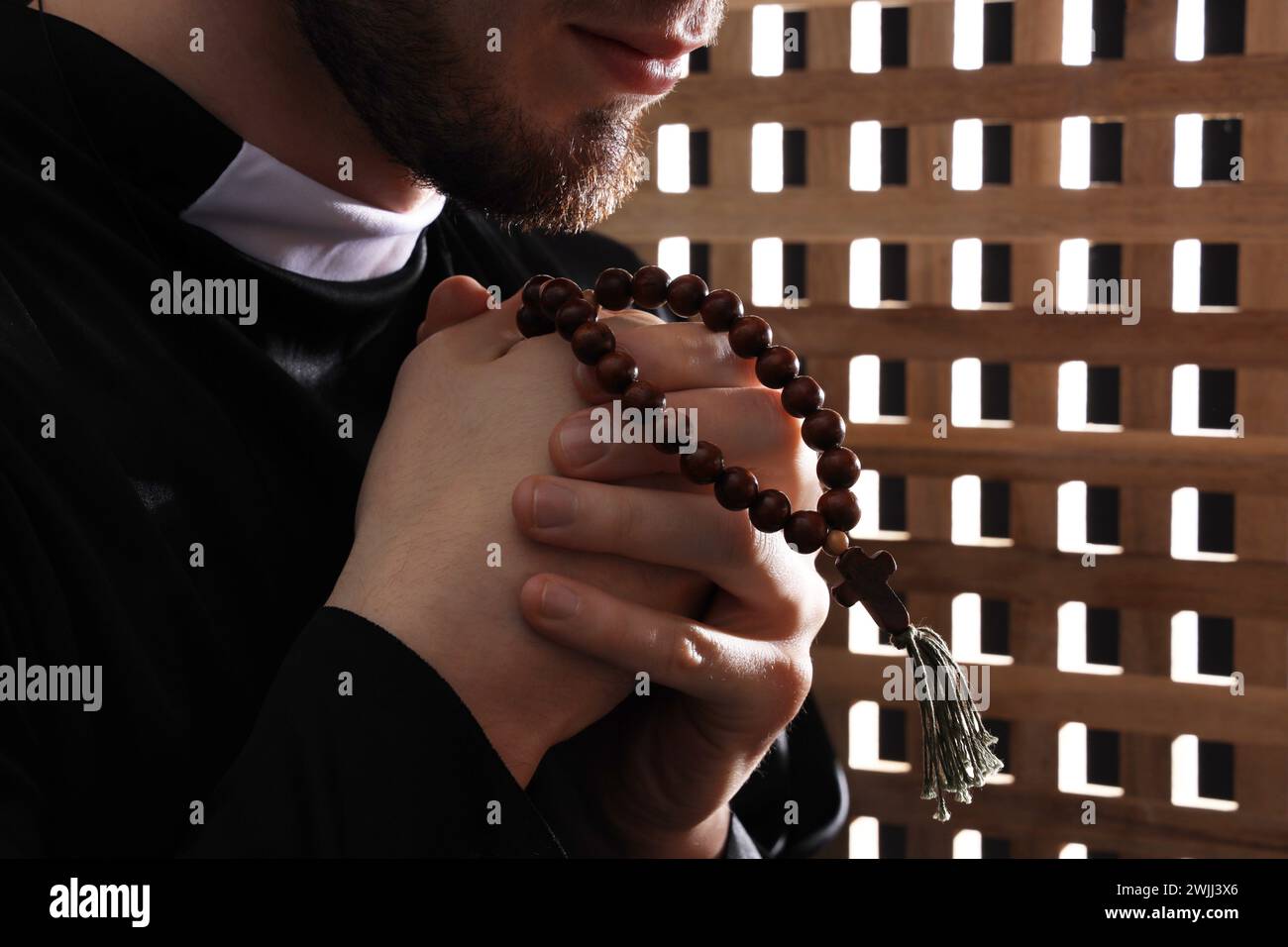Young priest praying in confession booth, closeup Stock Photo - Alamy