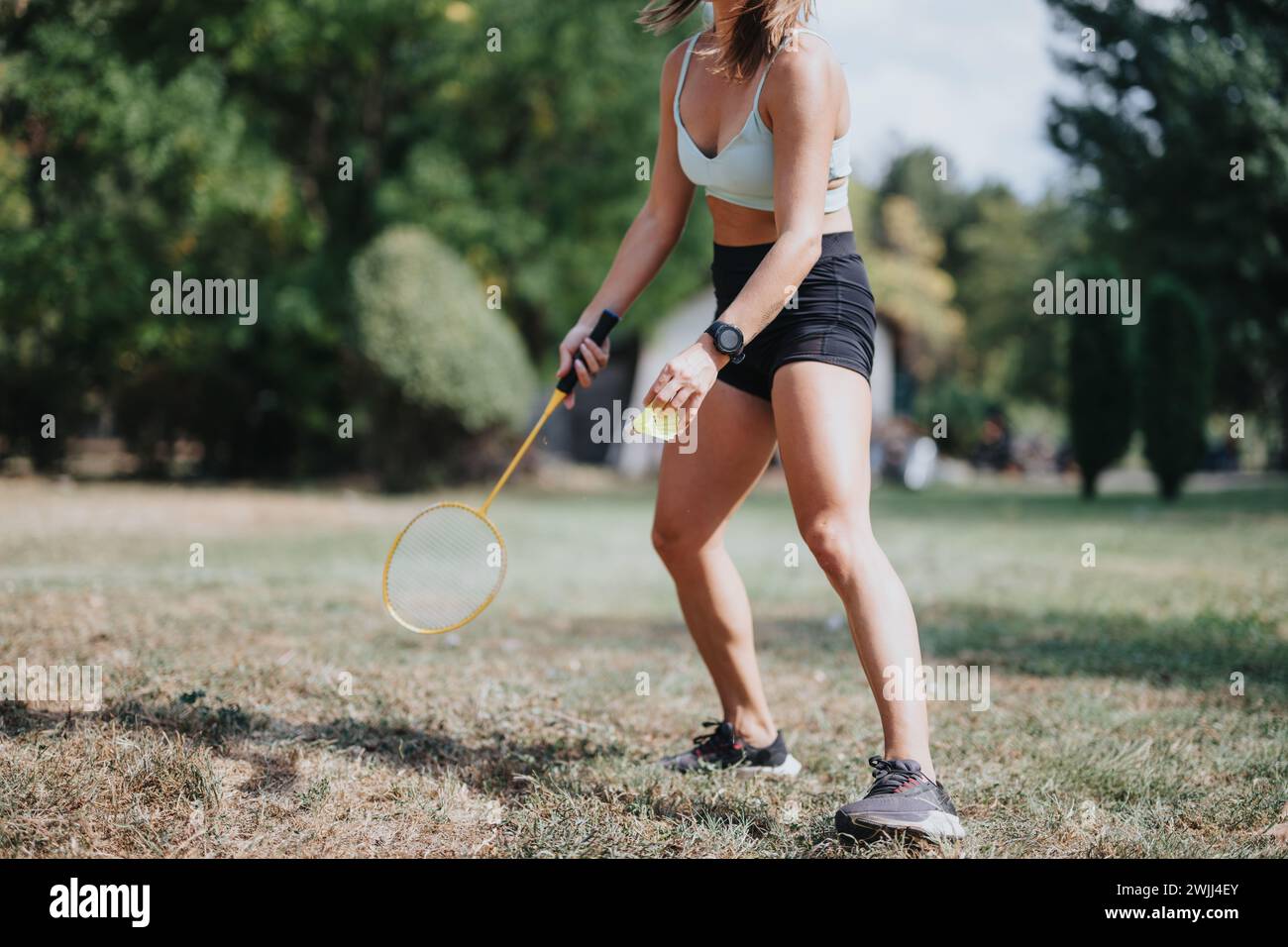 Attractive girl playing badminton in city park on a sunny day. She is ...