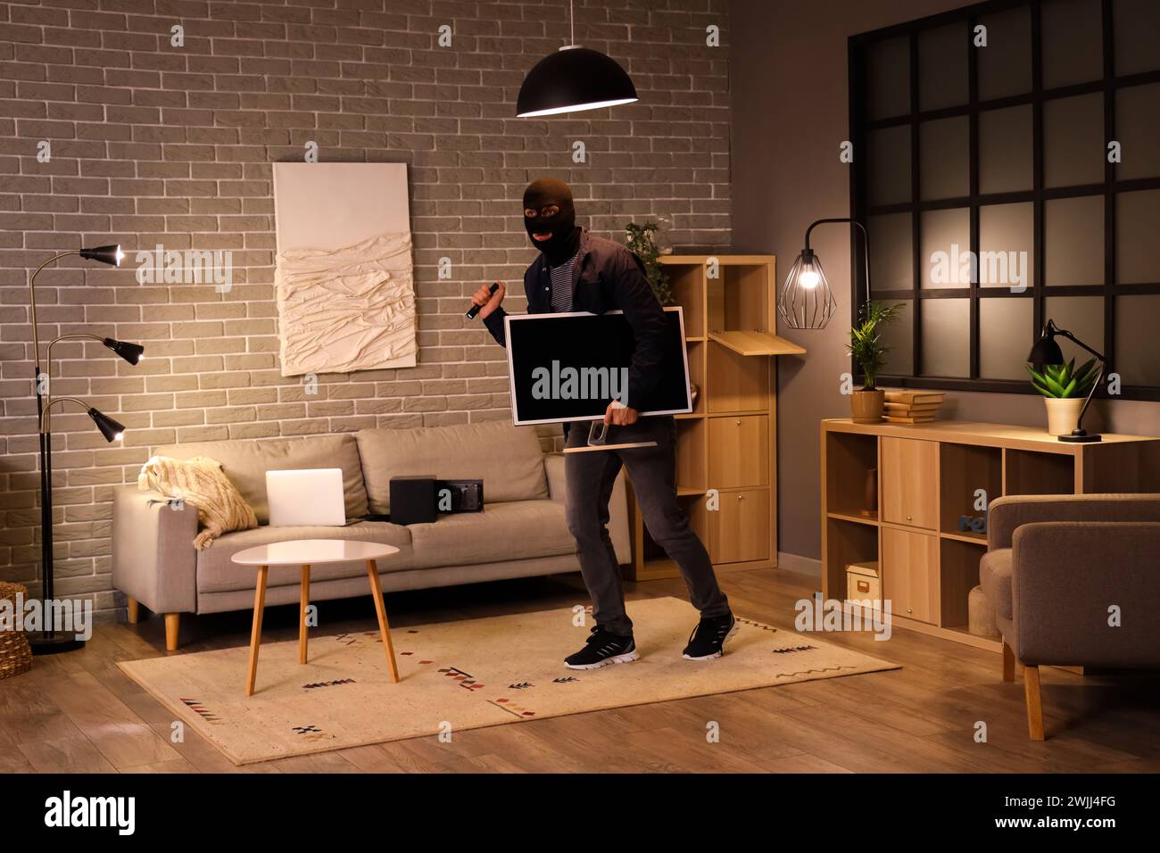 Male thief with flashlight stealing monitor in room at night Stock ...