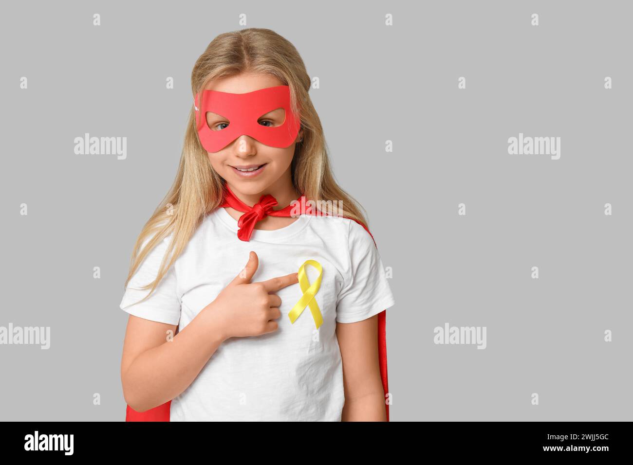 Cute teenage girl in superhero costume pointing at yellow ribbon on ...