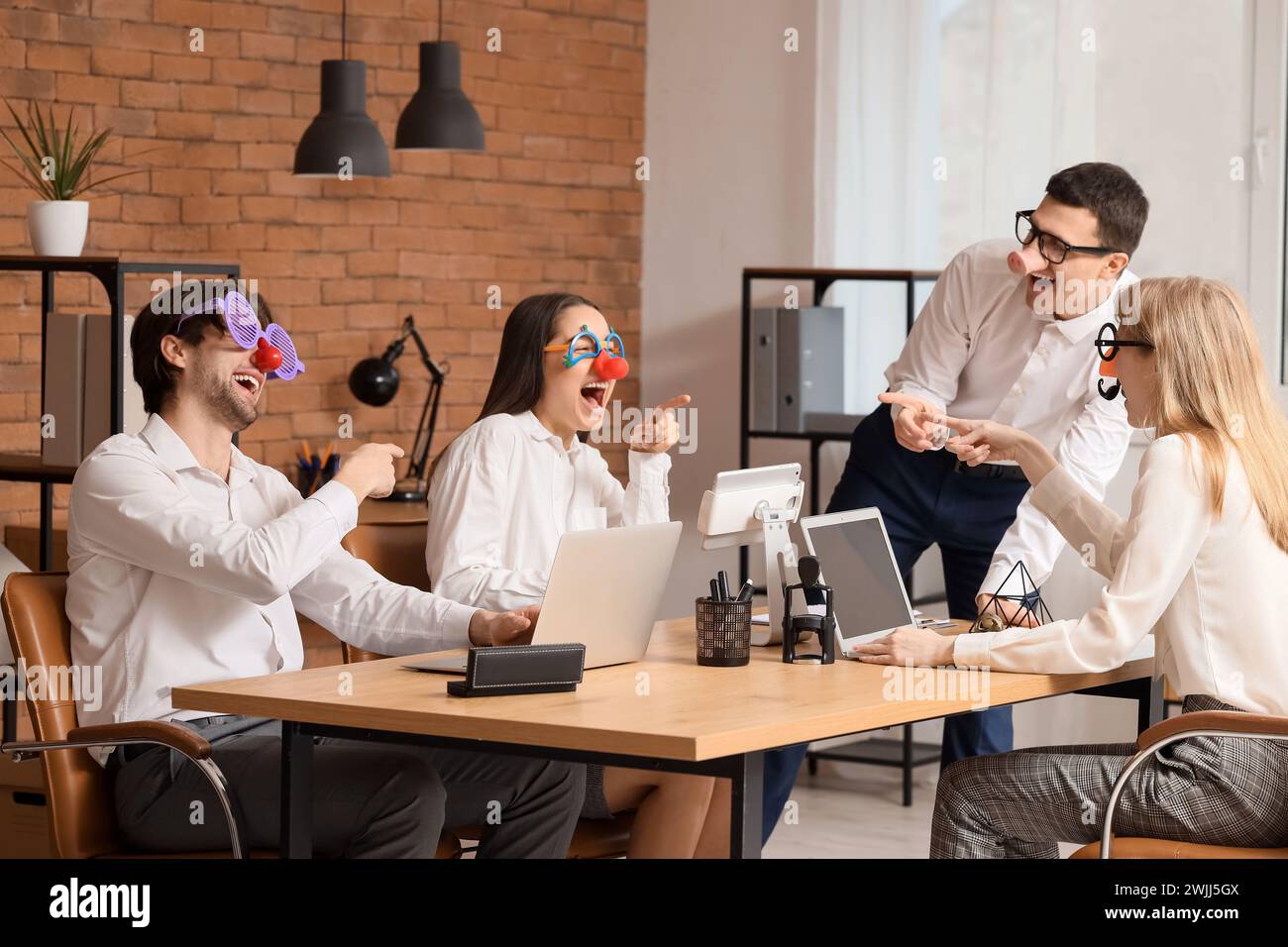 Business colleagues with funny disguise working in office. April Fools ...