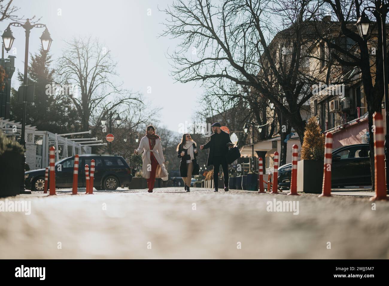 Urban scene with people walking on sunlit city street by shops and cars ...