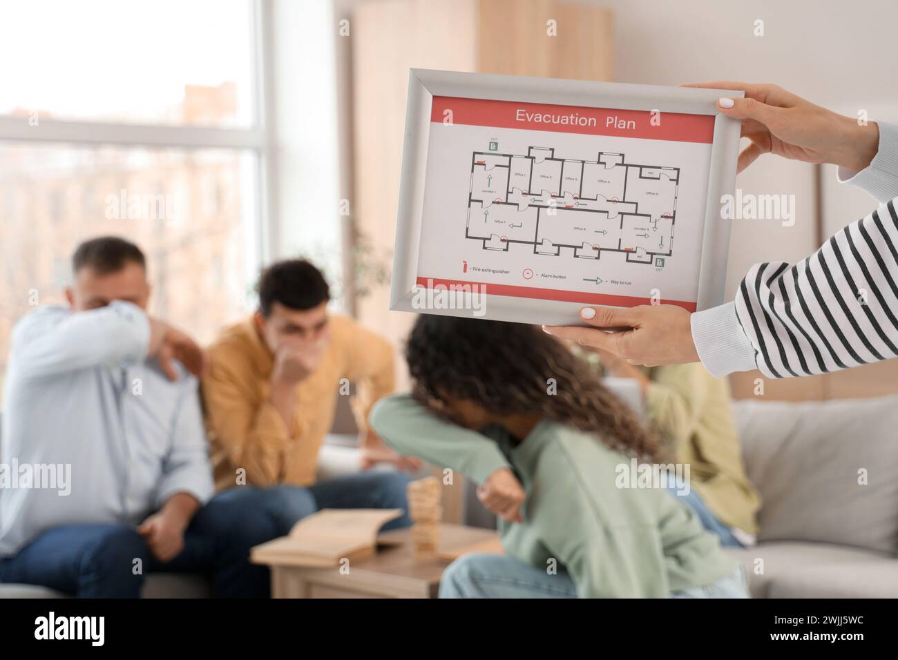 Young woman with evacuation plan and people choking on smoke in room ...