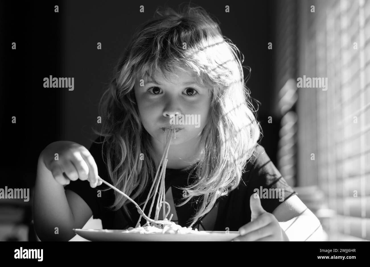 Cute little kid eating spaghetti pasta at home. Close up portrait of ...