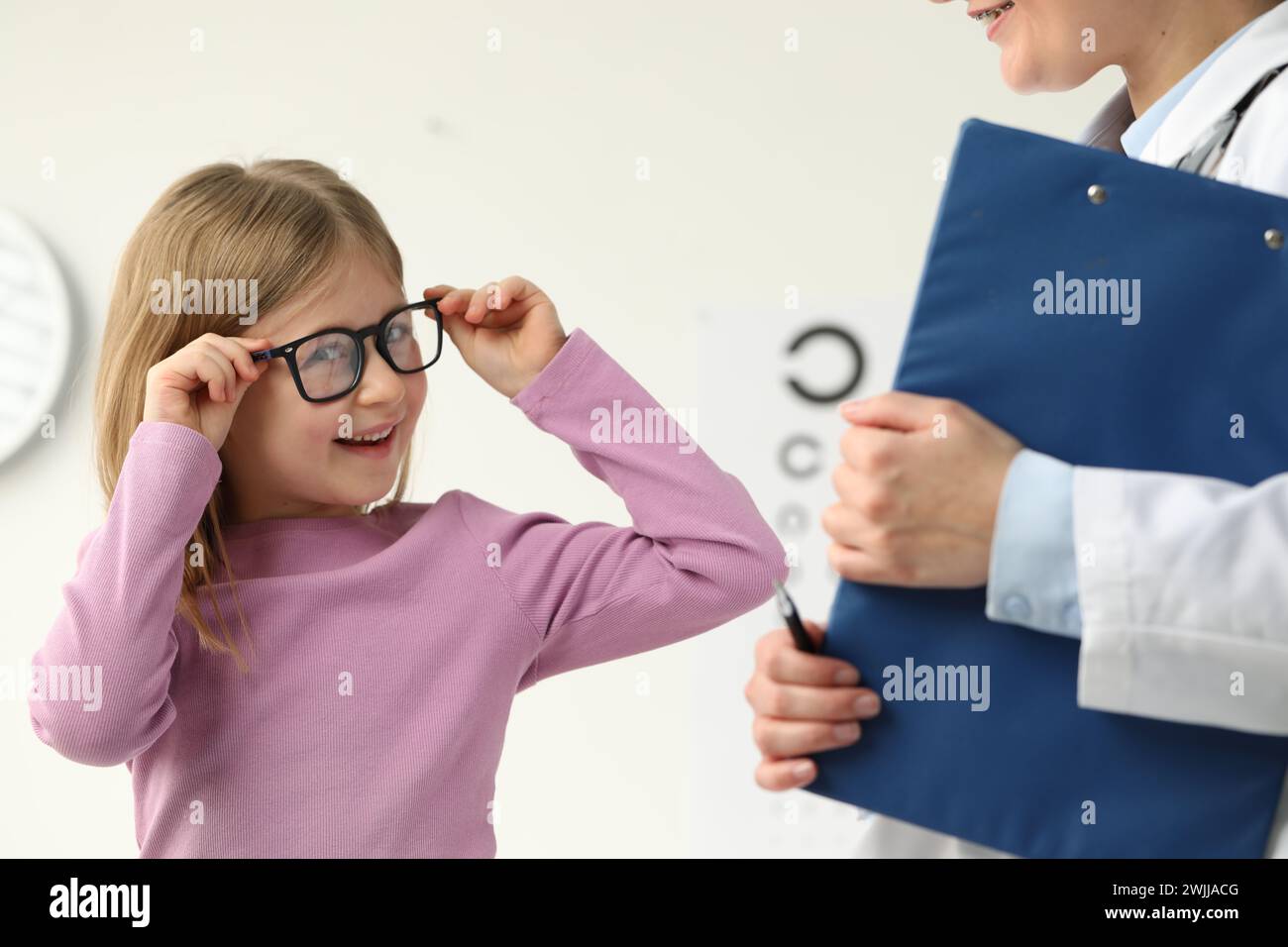 Vision testing. Little girl trying glasses at ophthalmologist office ...