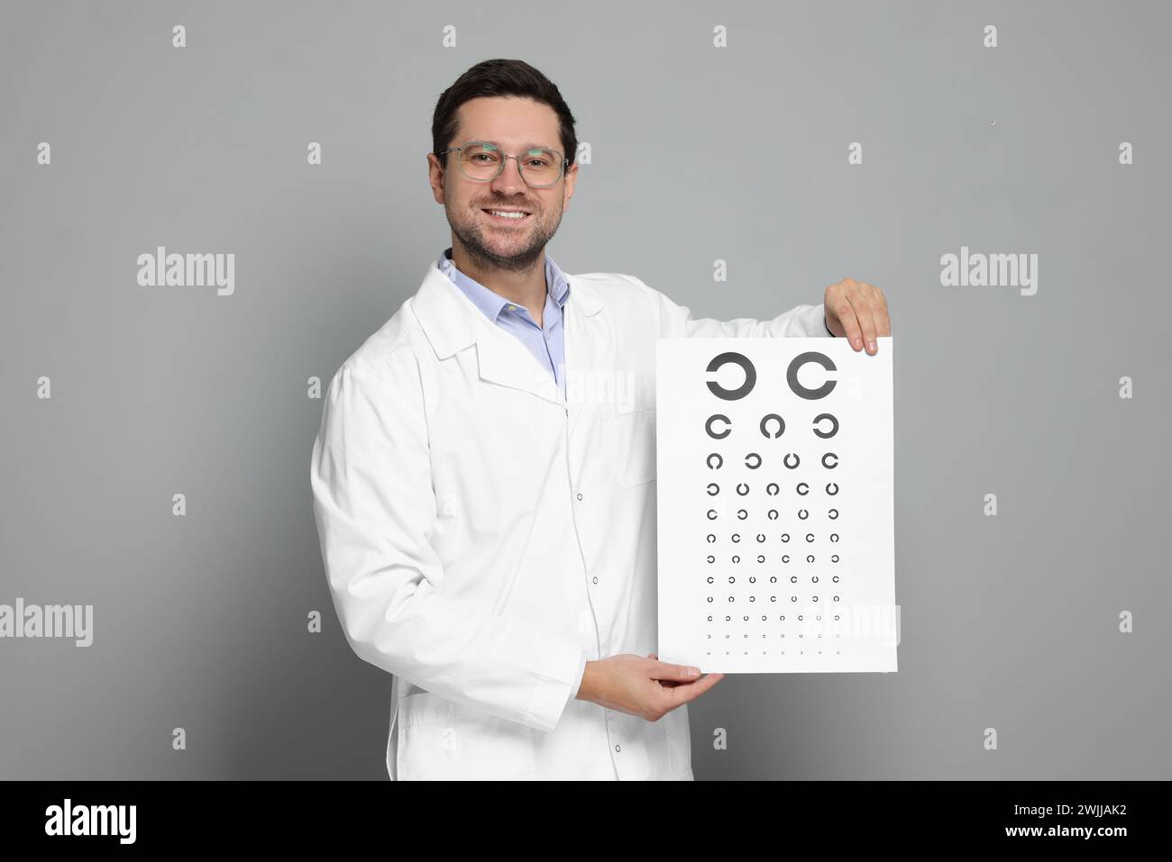 Ophthalmologist with vision test chart on gray background Stock Photo ...