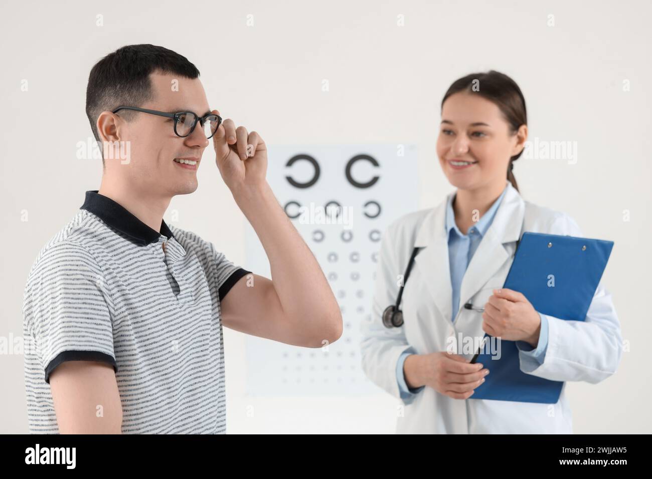Vision testing. Young man trying glasses at ophthalmologist office ...