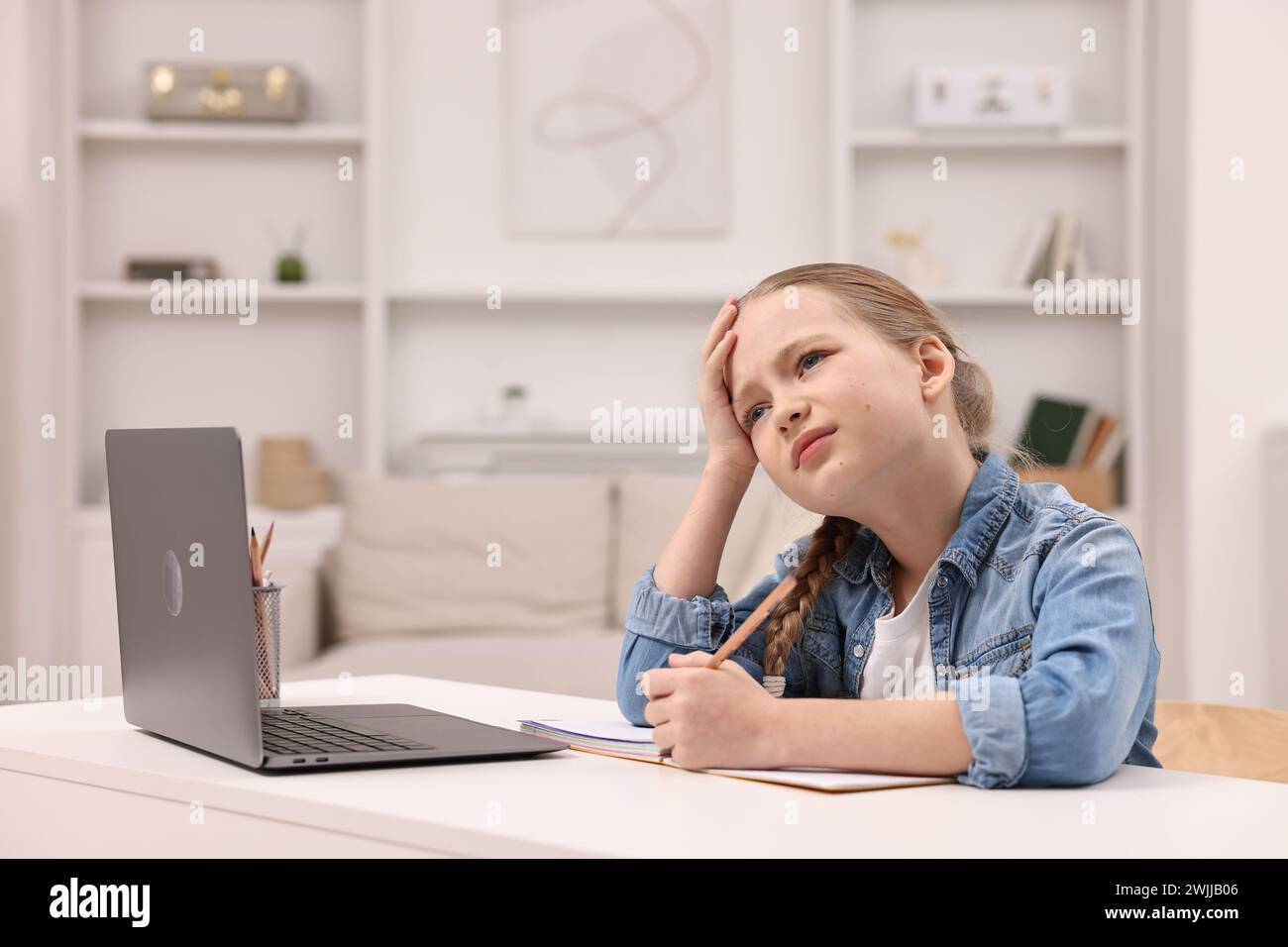 Little girl suffering from headache while doing homework at home Stock ...