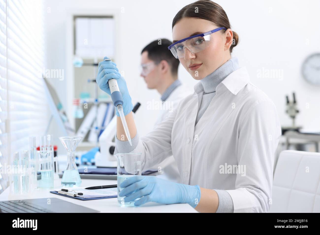 Scientist dripping sample into beaker in laboratory Stock Photo - Alamy