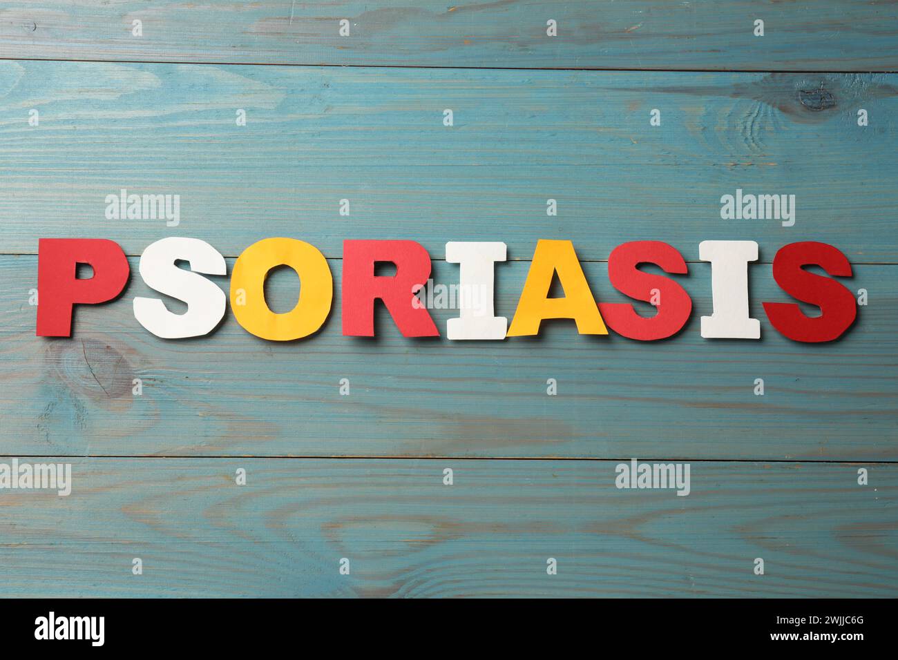 Word Psoriasis made of paper letters on light blue wooden table, top ...
