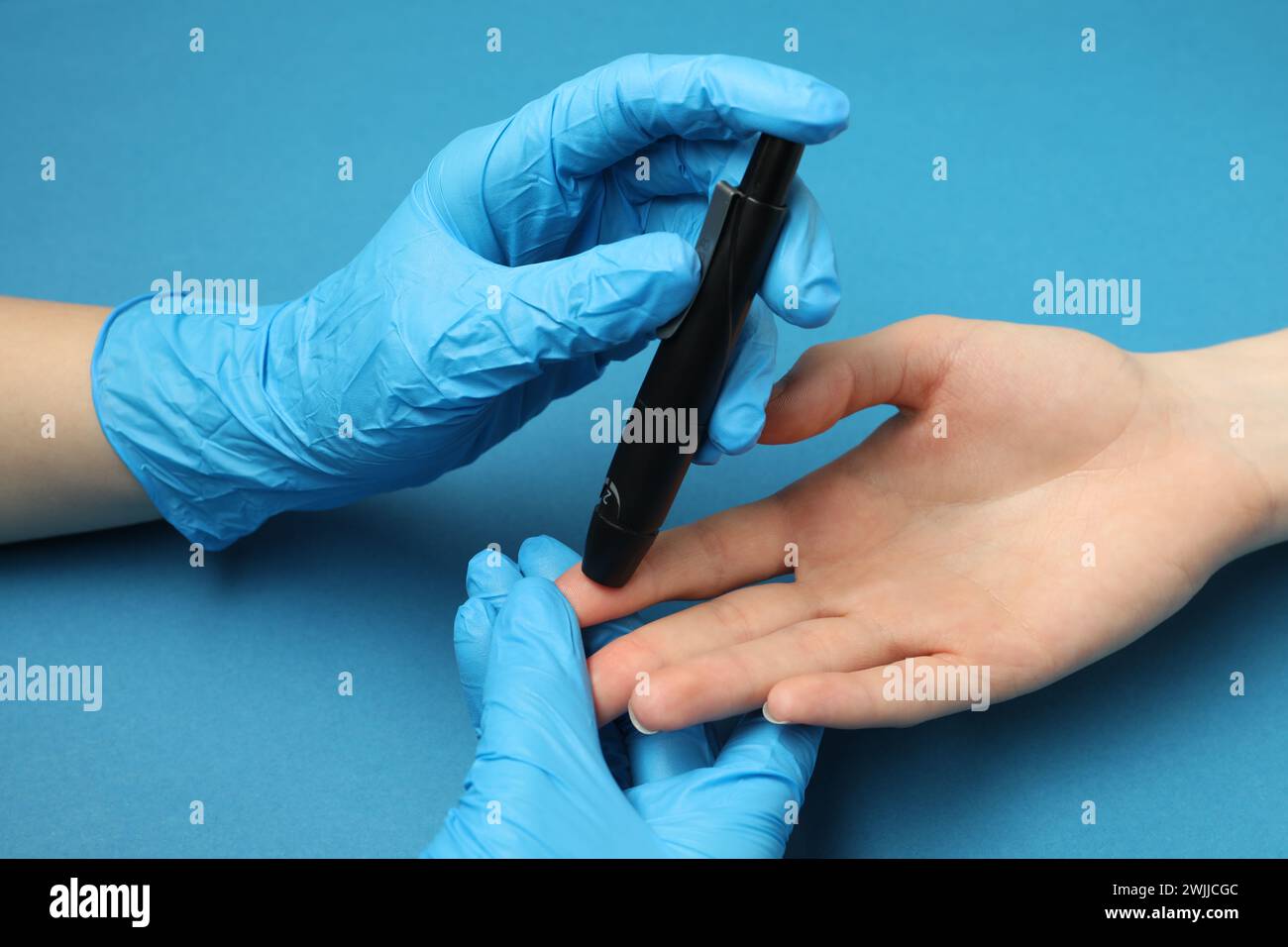 Diabetes. glucose testing. Doctor using lancet pen on blue background ...