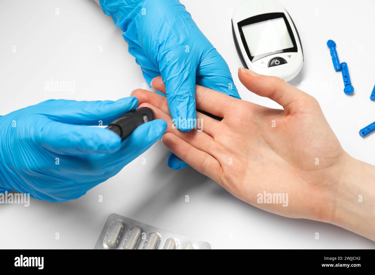 Diabetes. glucose testing. Doctor using lancet pen on white background ...