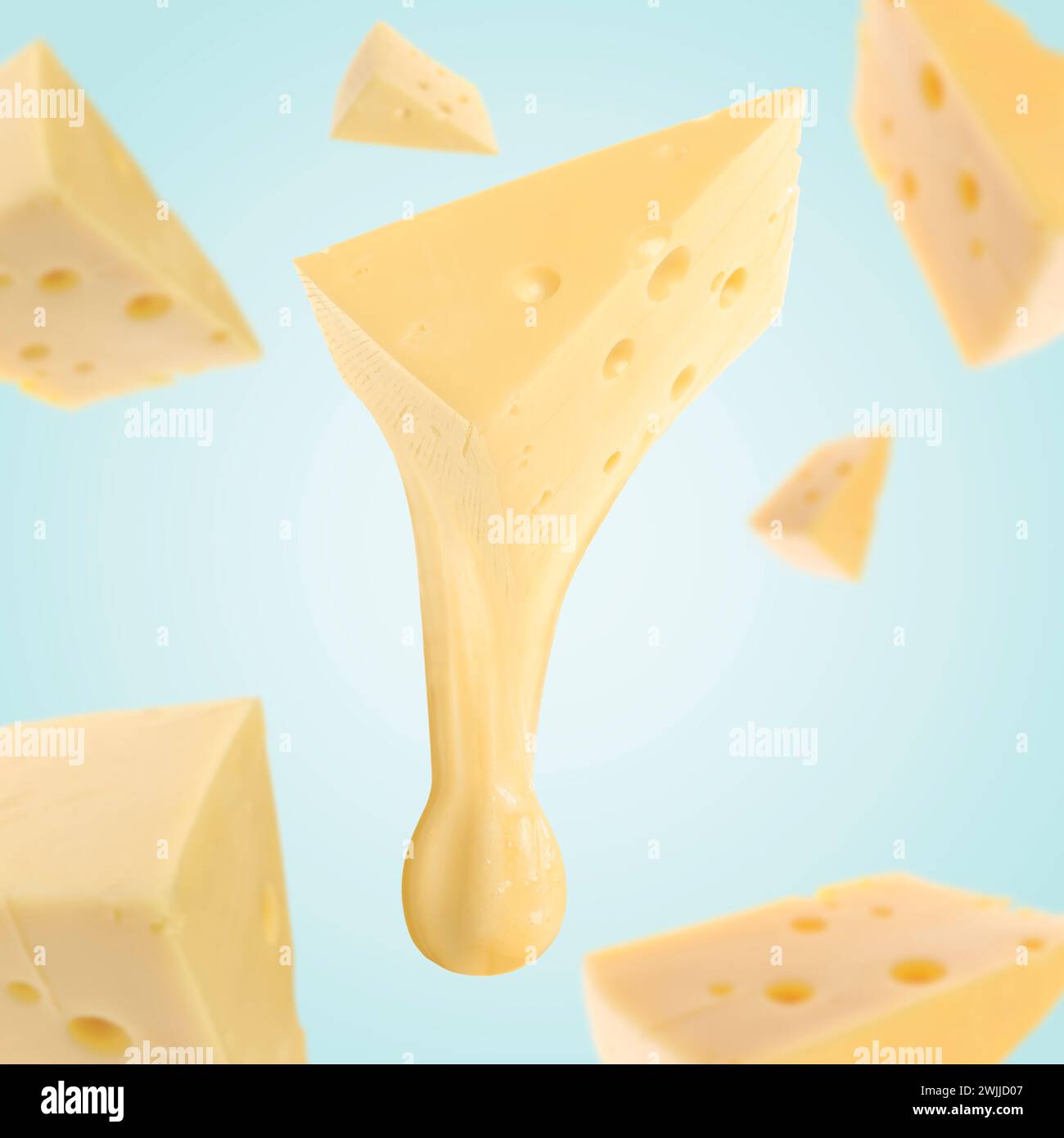 Pieces of cheese falling on light blue background Stock Photo - Alamy
