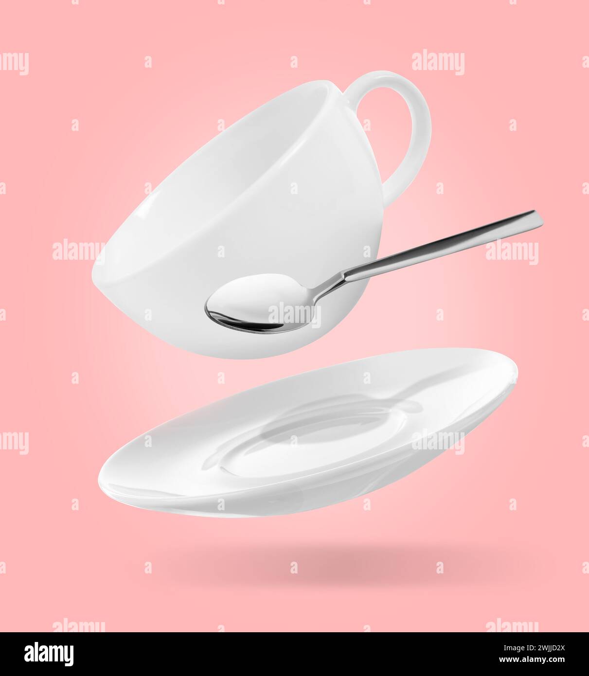 Spoon, cup and saucer falling on pink background Stock Photo - Alamy