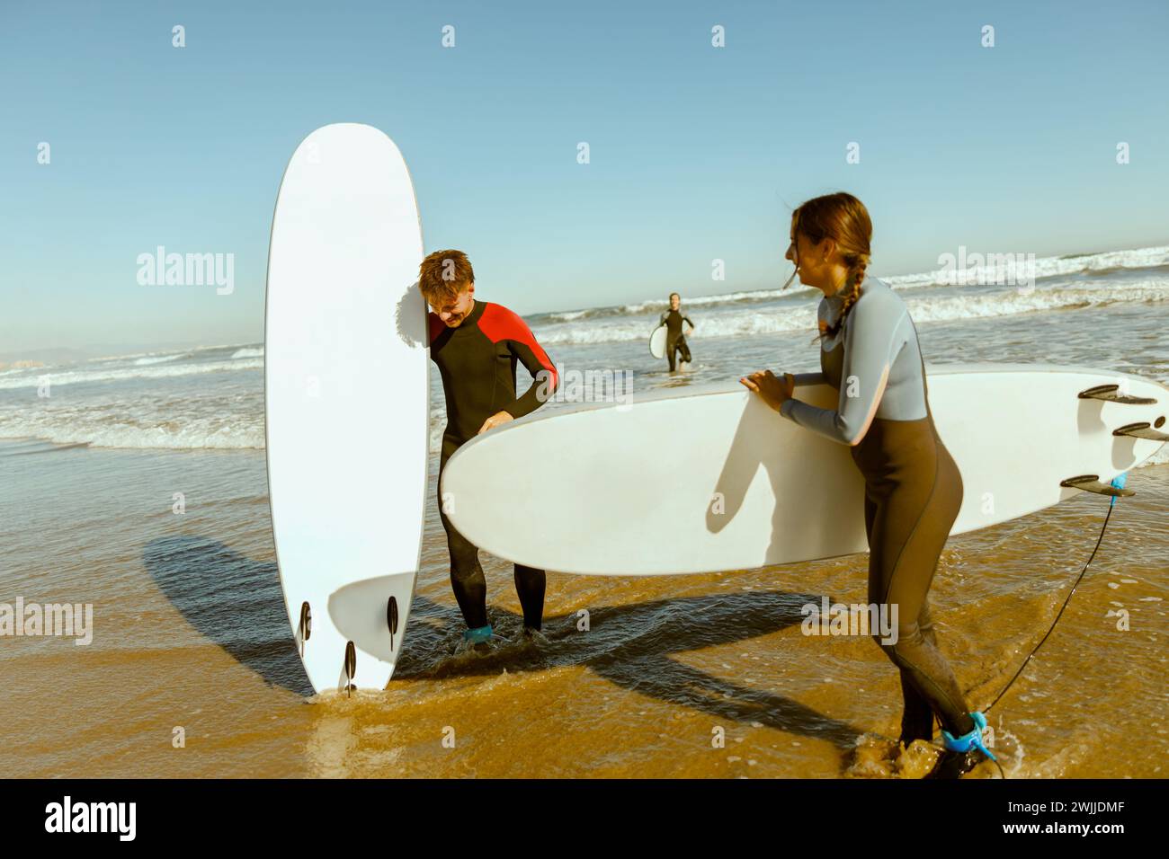 Surfers in wetsuits standing with surfboards and preparing for ride on ...