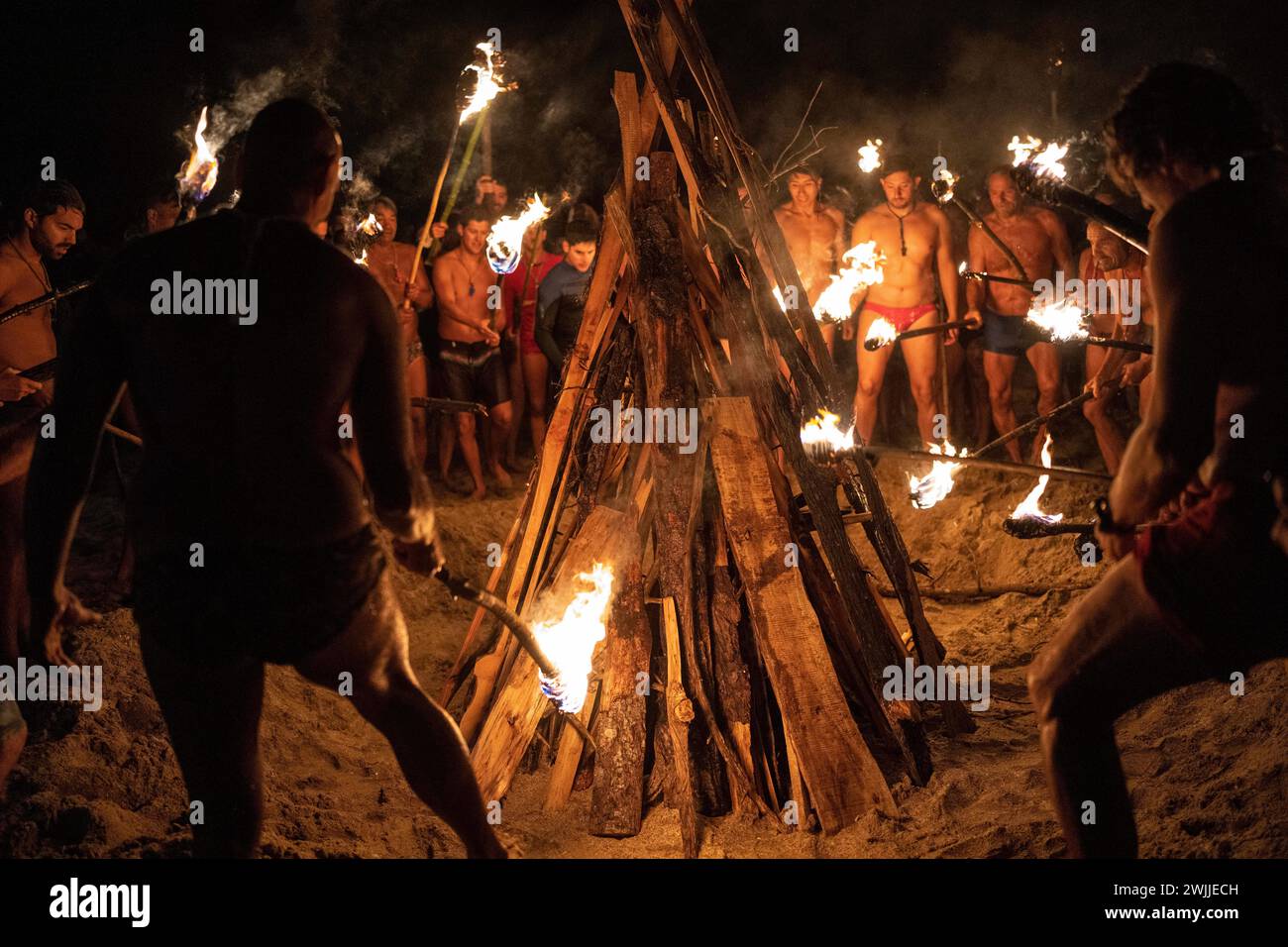 Lifeguards start a bonfire with torches to commemorate Lifeguard Day ...