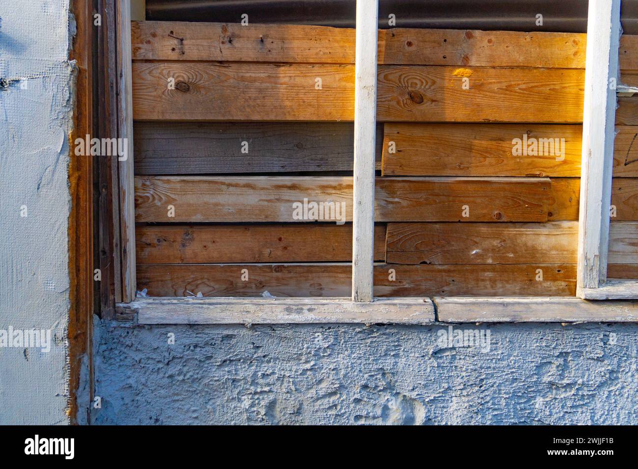Broken window covered with brown wooden slats as a makeshift solution ...