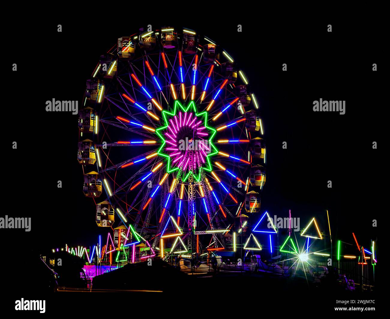 Night image of giant Ferris wheel illuminated and spinning at low speed ...