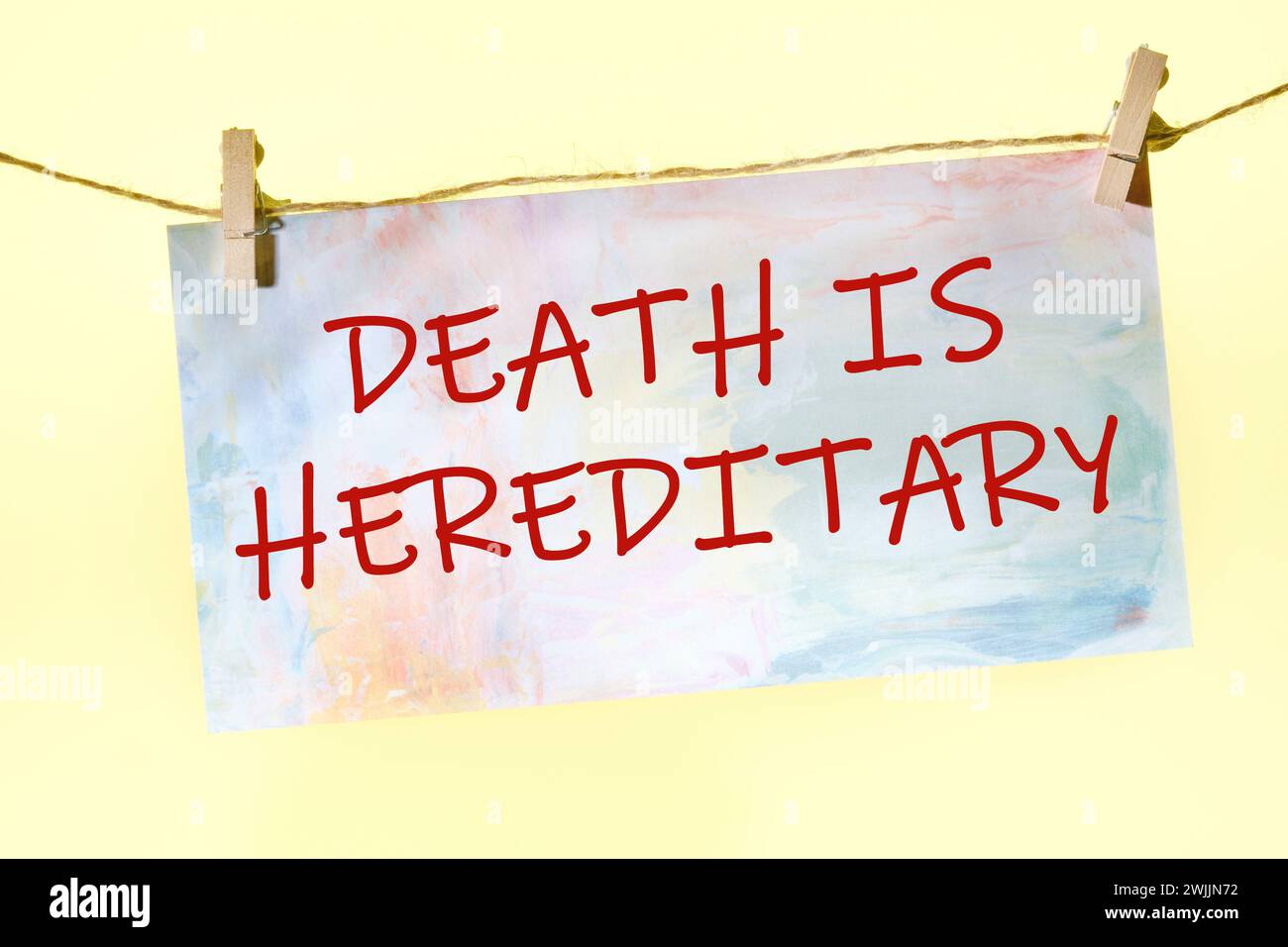 DEATH IS HEREDITARY text written on a piece of paper fixed on a rope ...