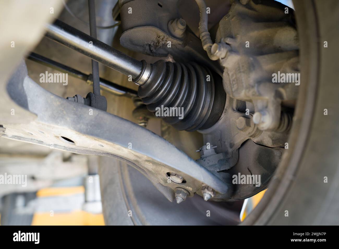 Closeup car's suspension system, focusing on the axle and CV joint area ...