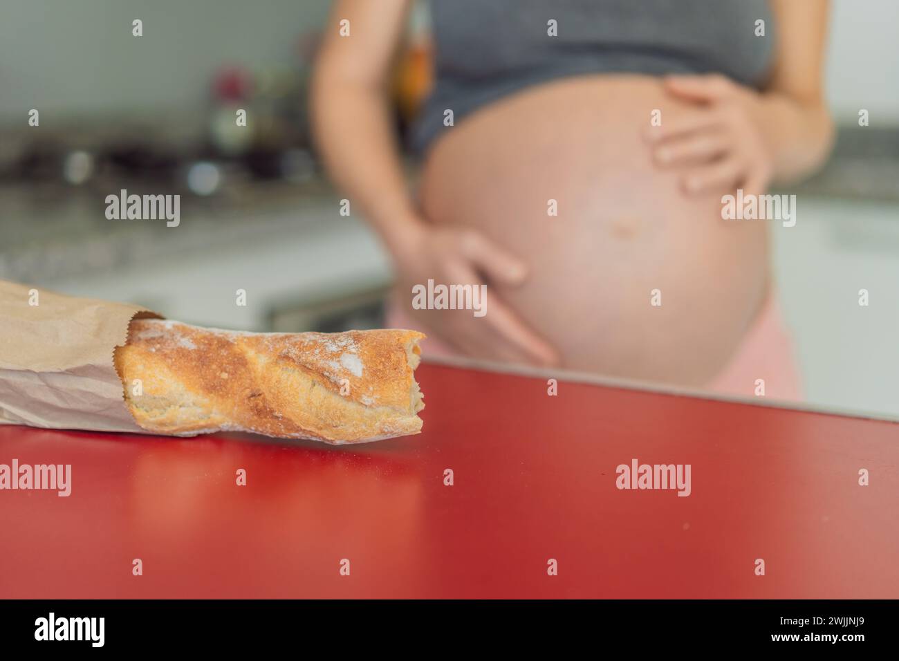 Pregnant woman eating bread in the kitchen. Exploring the impact of ...