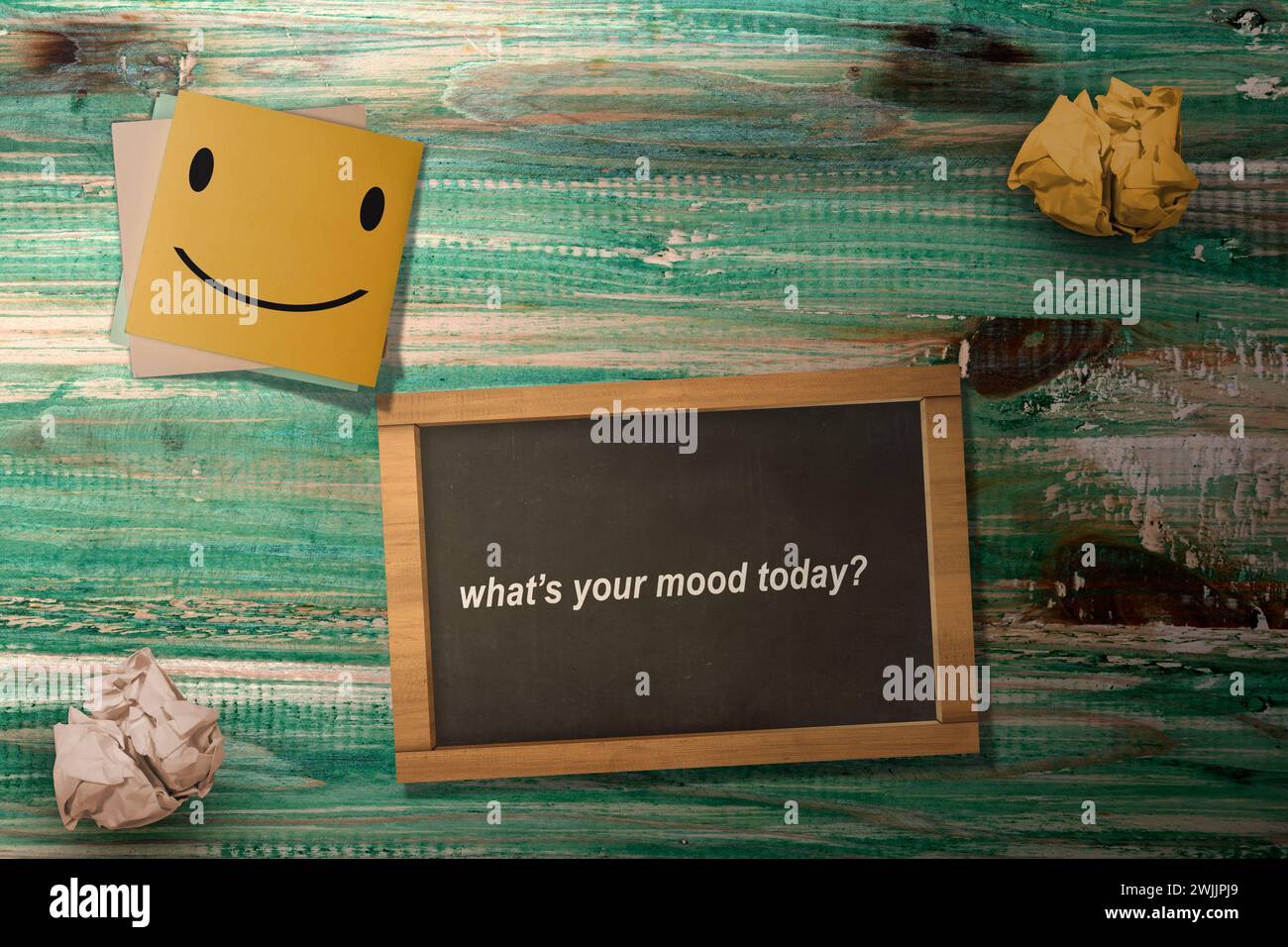 A stack of paper with a smile symbol and a small chalkboard with a ...