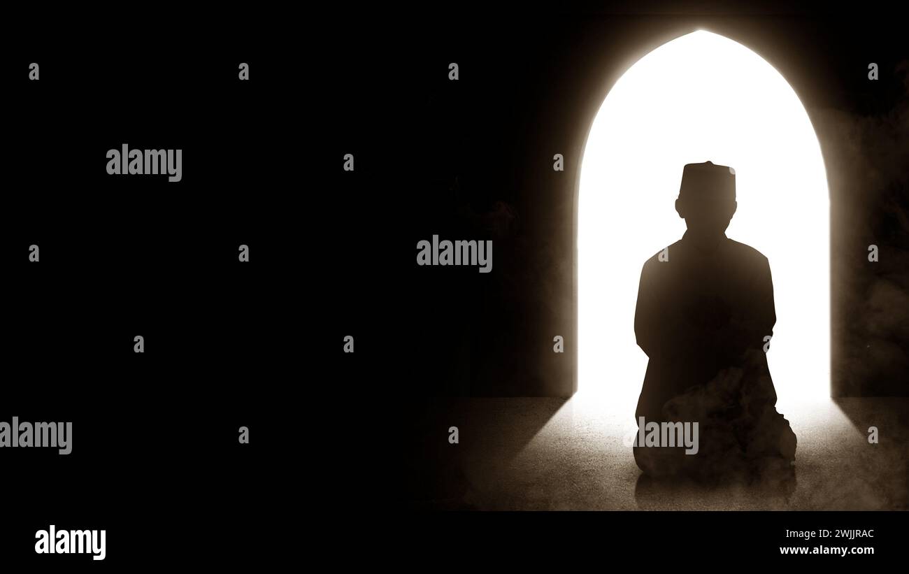 Silhouette of a Muslim man sitting and raising her hands and praying to ...