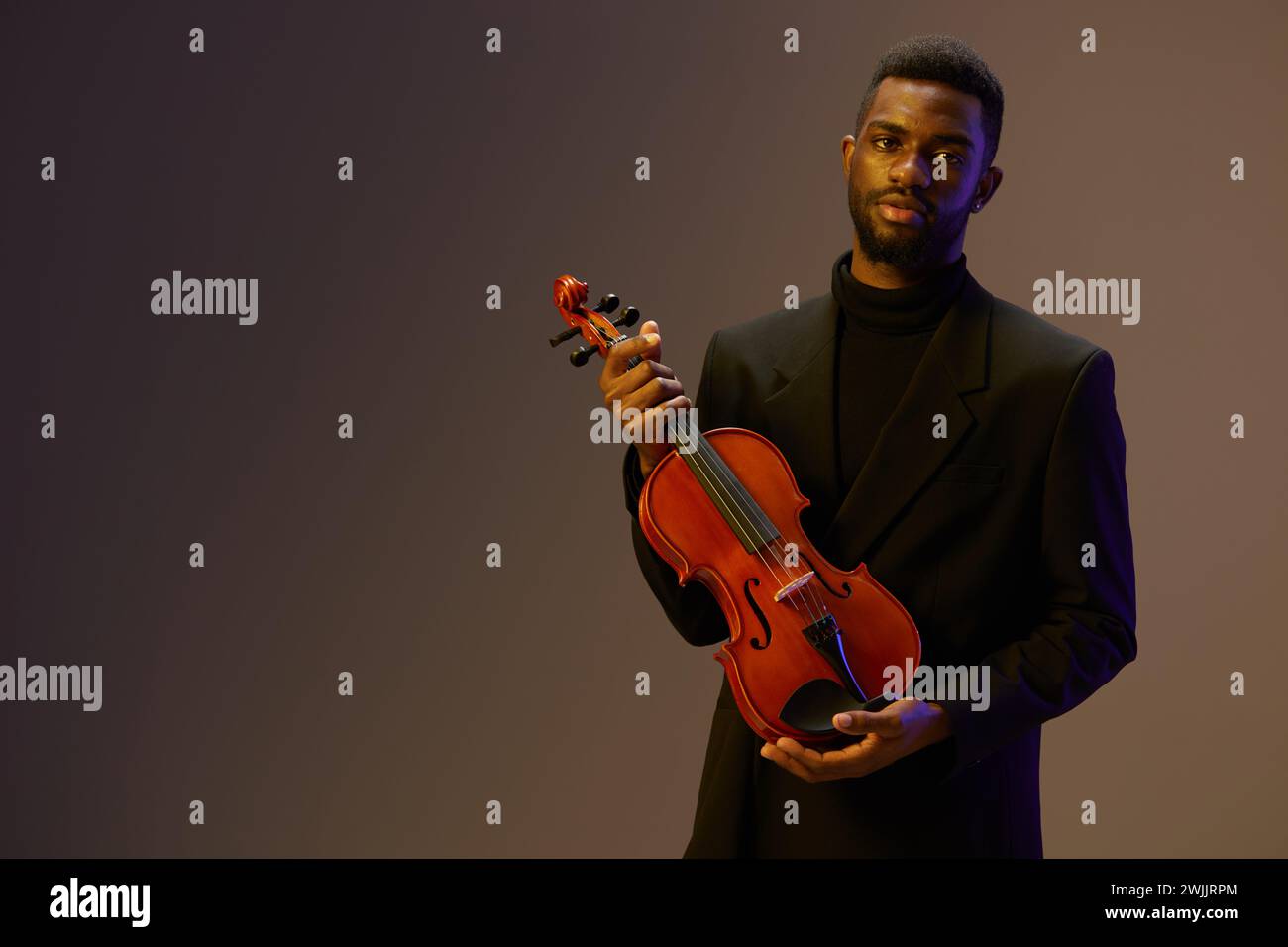 Professional African American man in suit holding a violin against dark ...