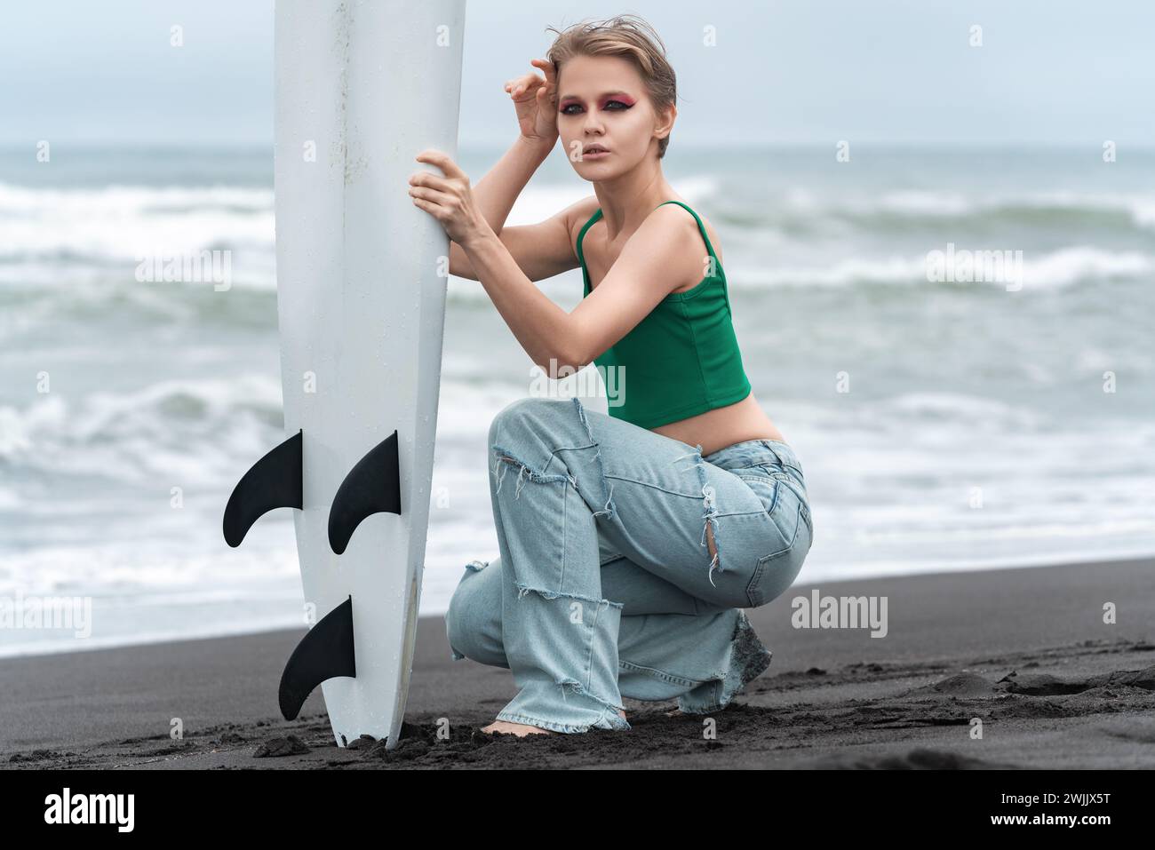 Portrait of hipster woman surfer holding surfboard vertically, sitting ...
