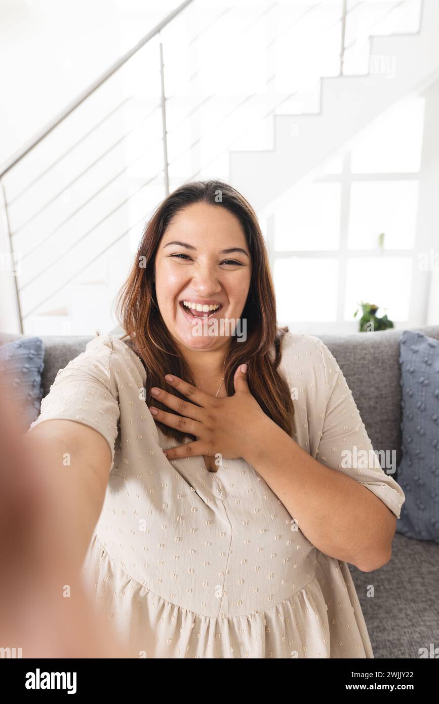 Joyful young plus size biracial woman taking a selfie at home, with ...