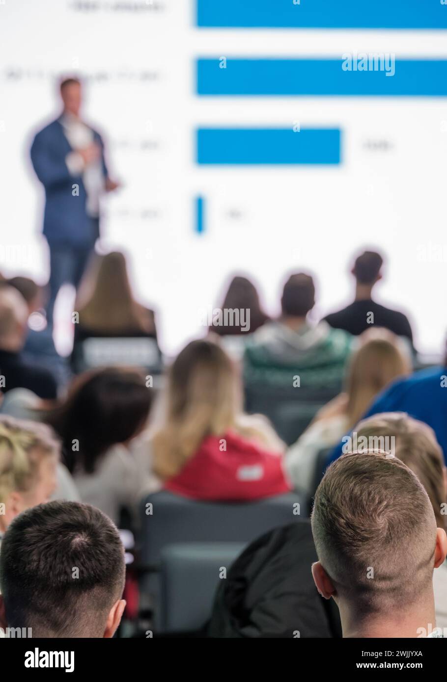 Blurred presenter at a business conference with a focused diverse ...