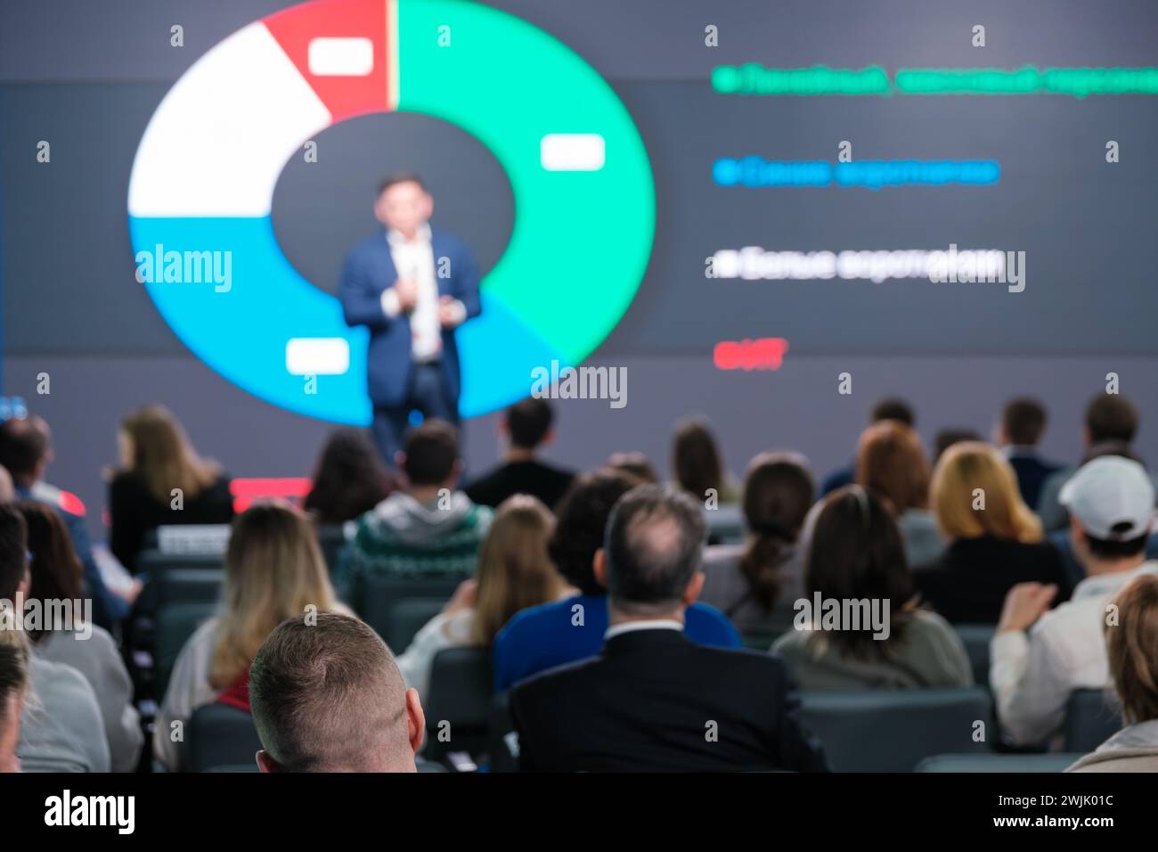 Blurred audience attentively listening to a speaker giving a ...